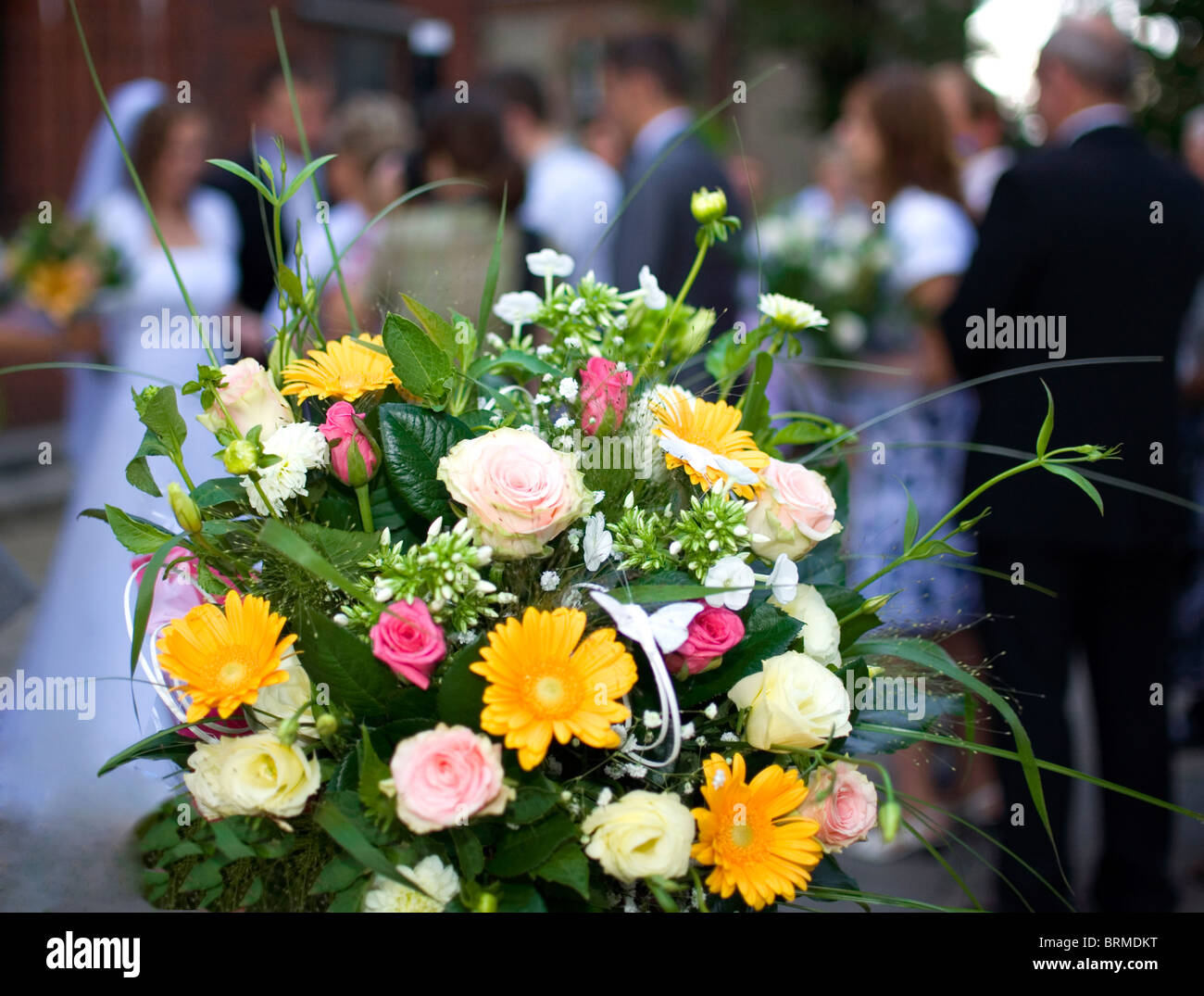 Wedding bouquet with yound couple and wedding guest in blurry ...