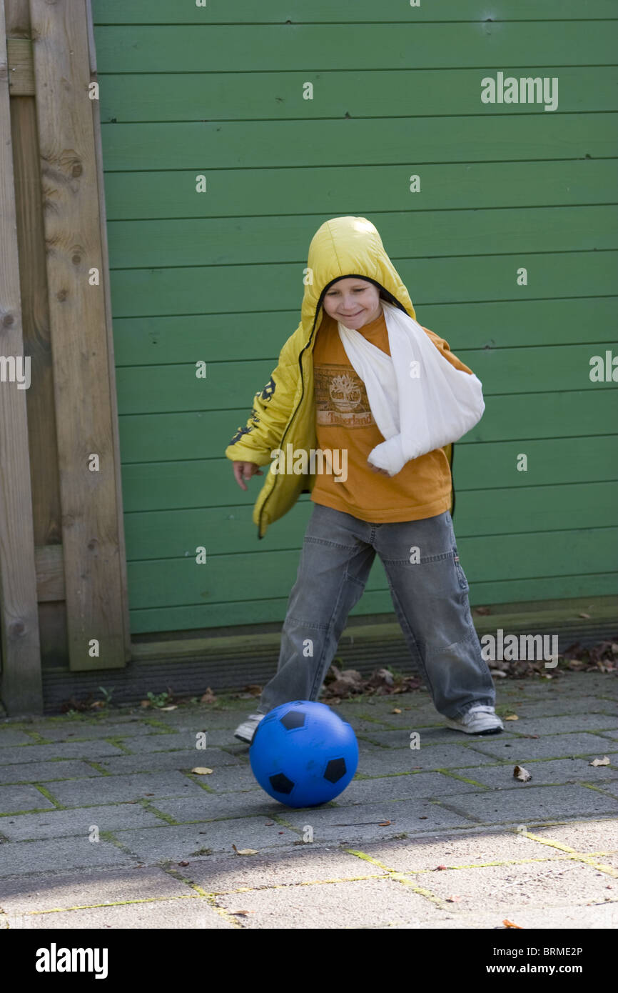Autistic young boy with arm fracture playing soccer ball outside Stock ...