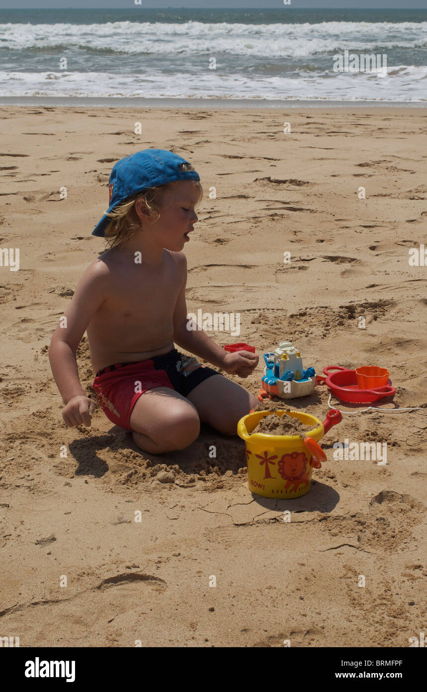 Boy sitting and playing on beach Stock Photo - Alamy