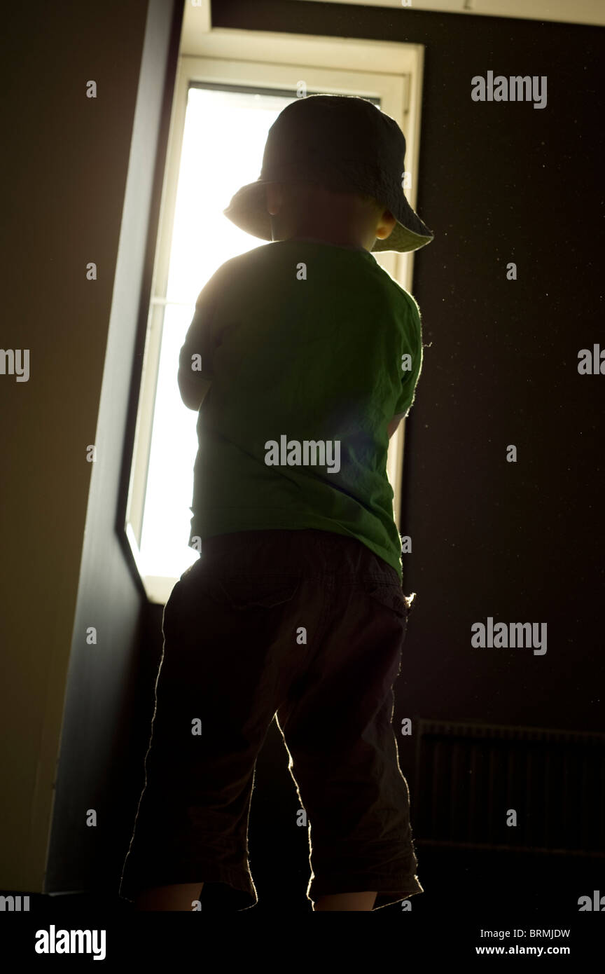 Young boy standing by window Stock Photo - Alamy
