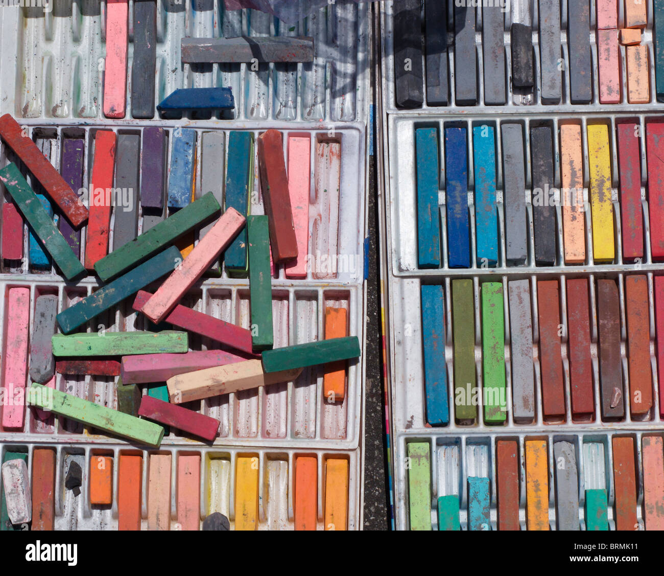 multicolored bars of artist's chalk in boxes and scattered on top of ...