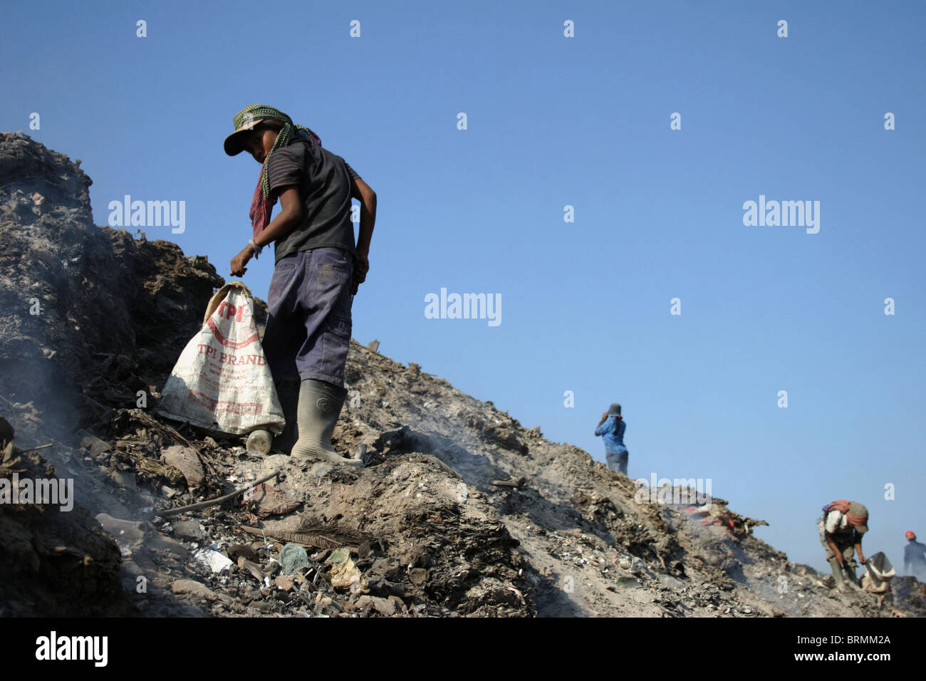 A young child laborer boy is carrying a garbage bag to collect trash at ...