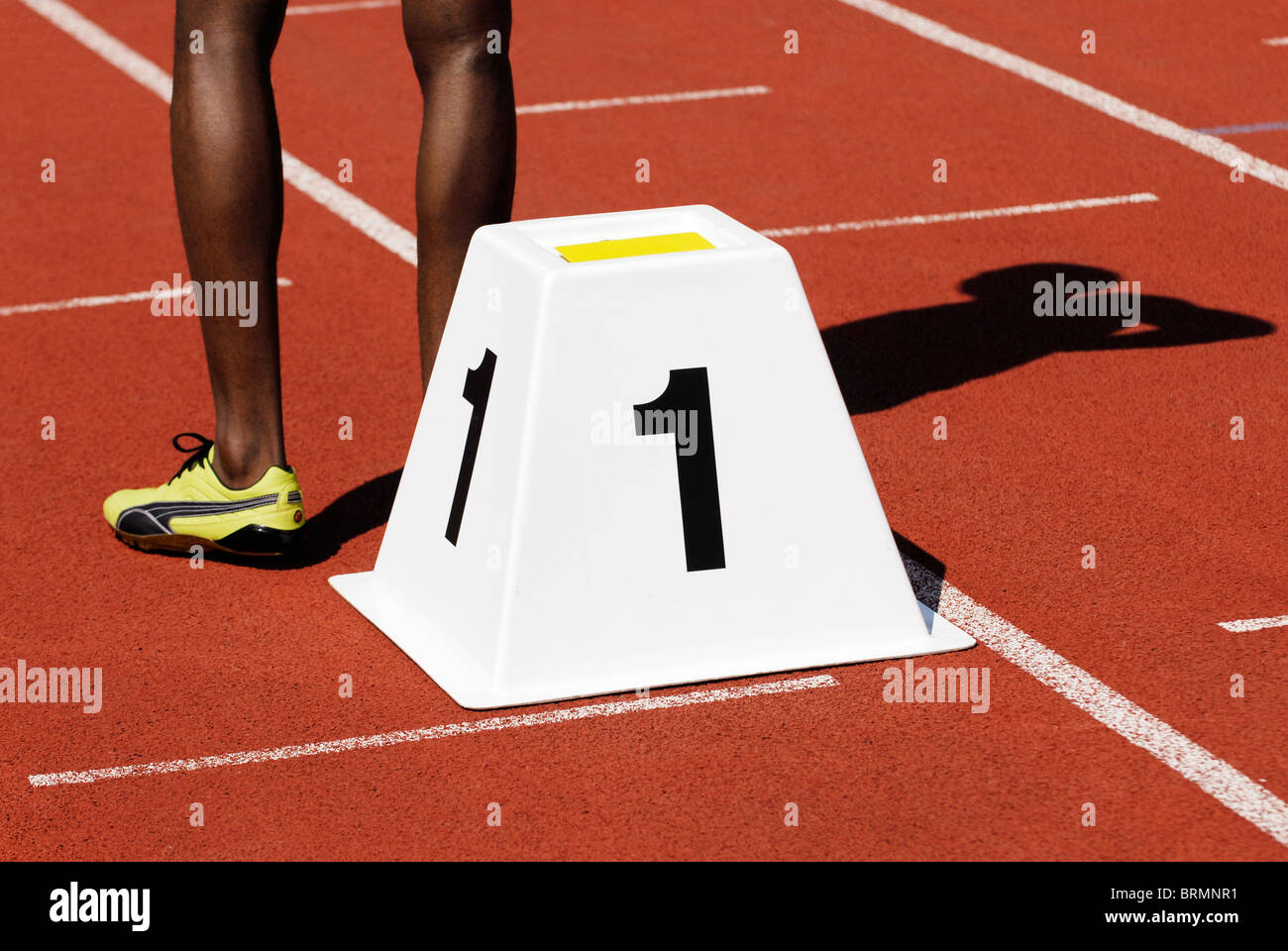 legs of a male sprinter next to starting block number one on athletic ...