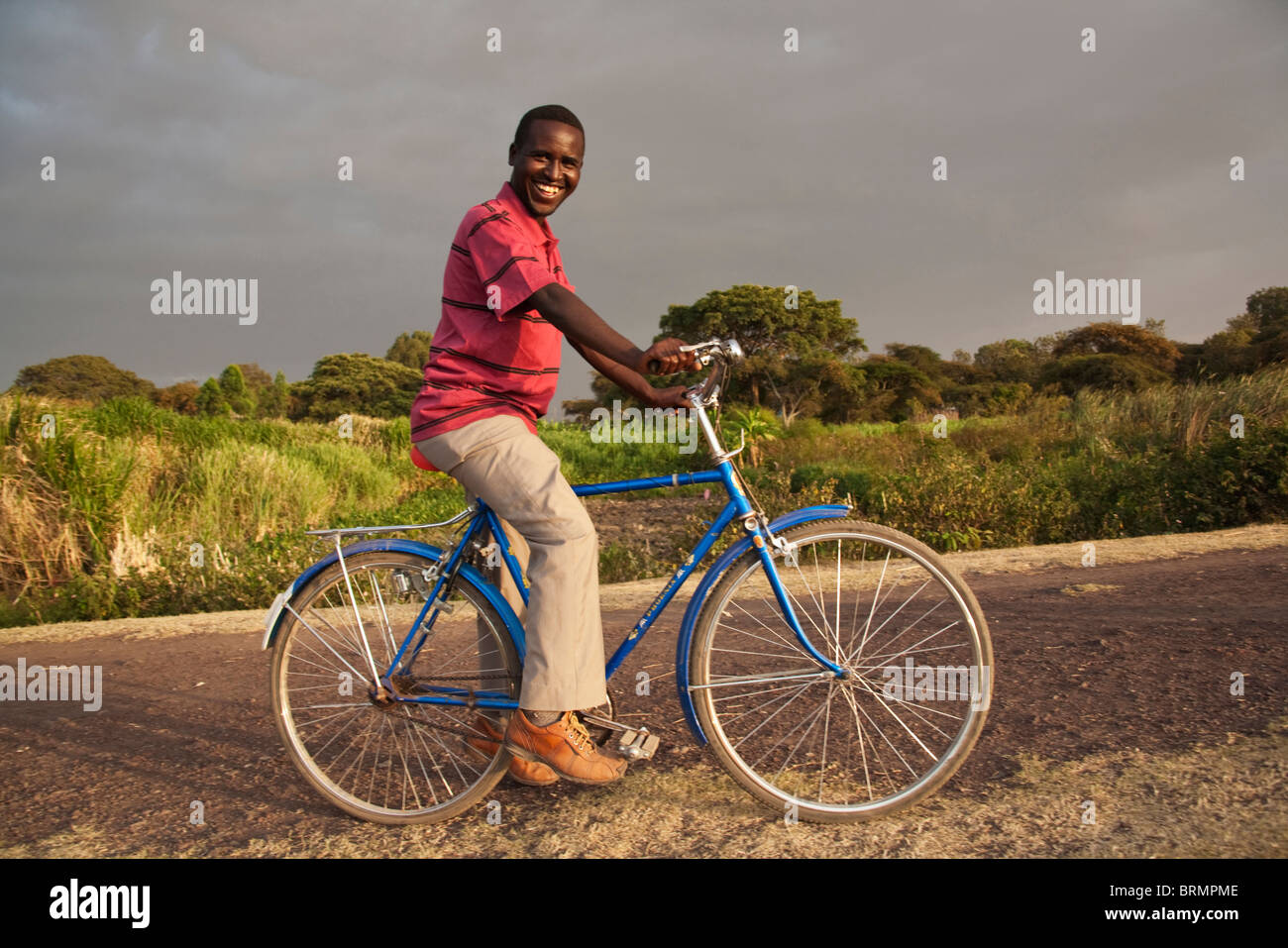 A friendly Ethiopian man pausing while riding a bicycle Stock Photo - Alamy