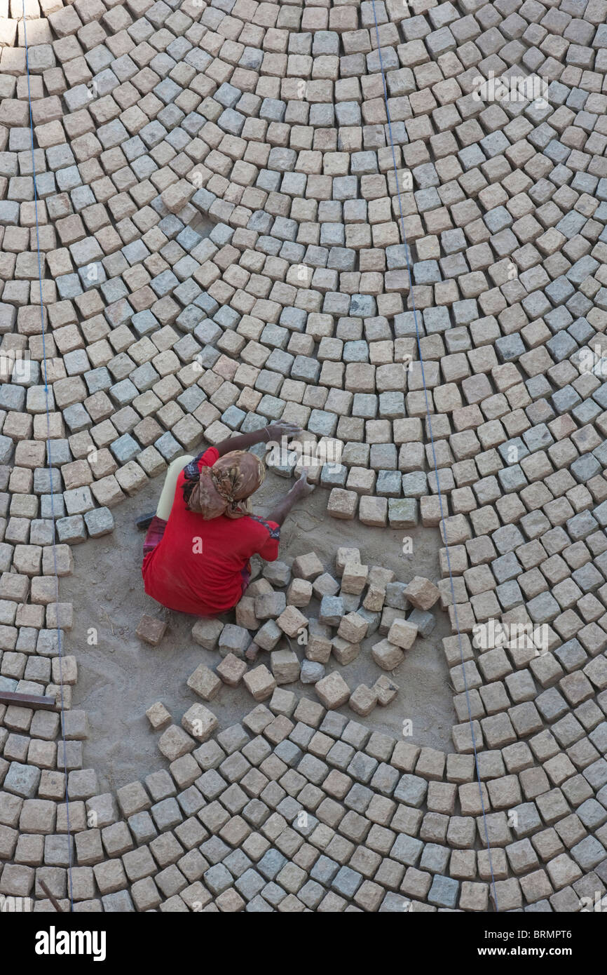 Overhead view of a worker laying a cobble stone pavement in a technique ...