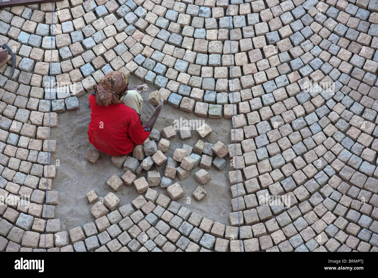 Overhead view of a worker laying a cobble stone pavement in a technique ...