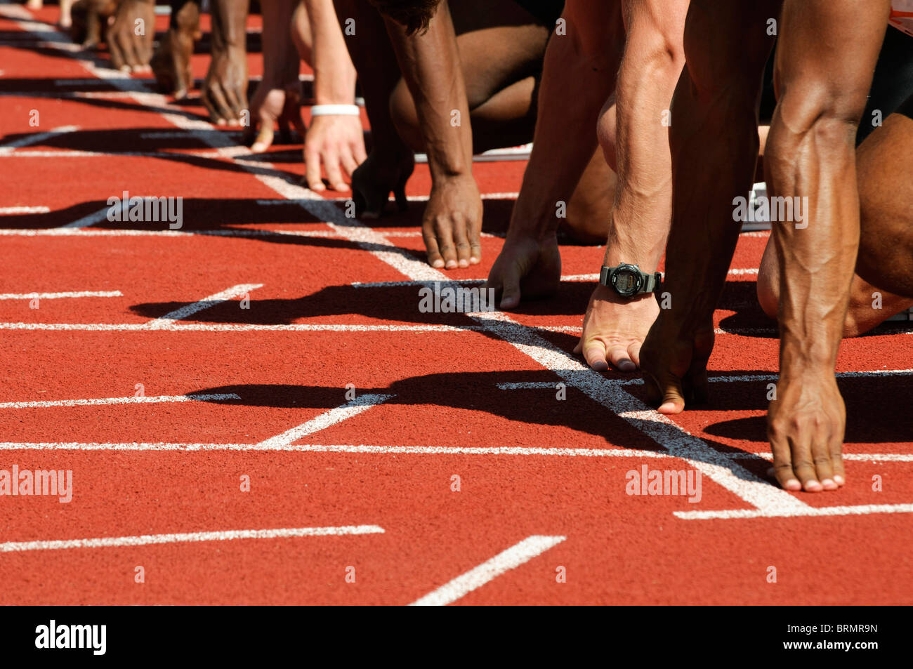 male sprinters line up their hands on the starting line at track and ...