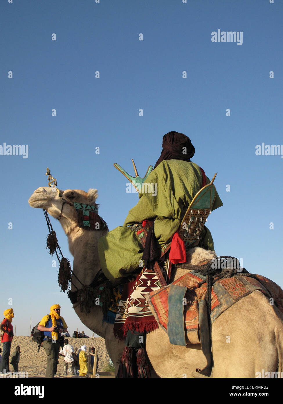 Tuareg man on a camel dressed in traditional robes watching a ...
