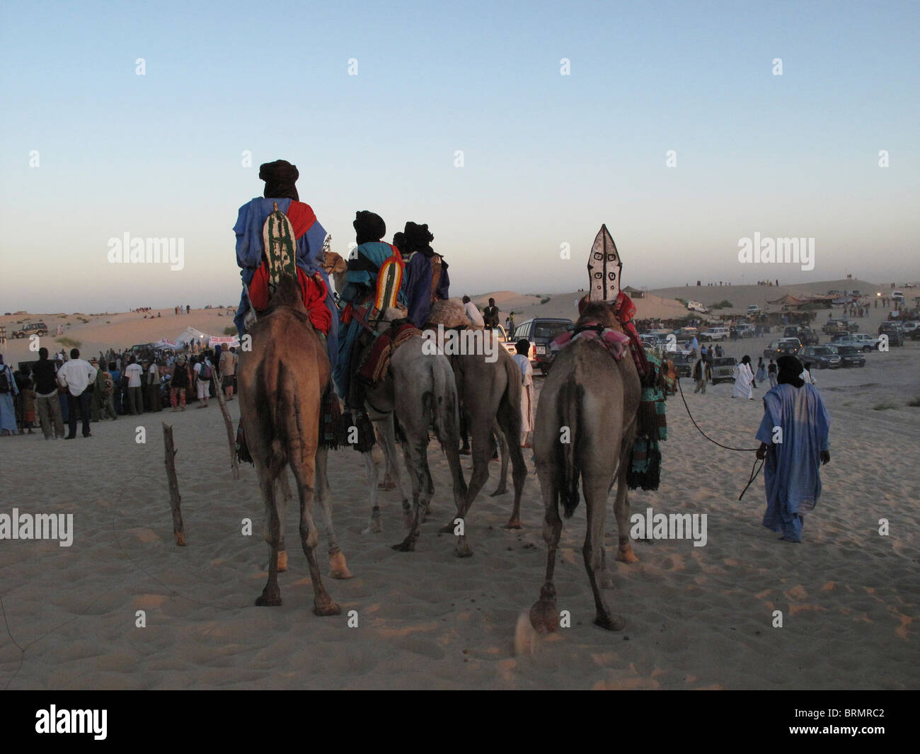 Tuareg men on camels dressed in traditional robes watching a ...