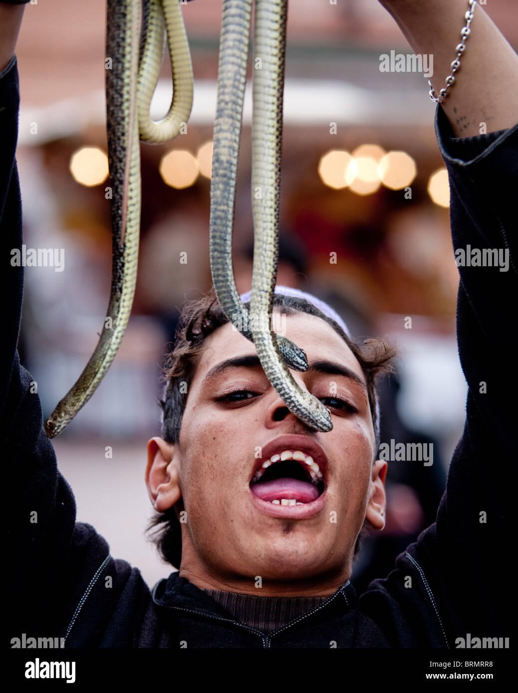 A young man displays some of his snake charming skill in the market ...