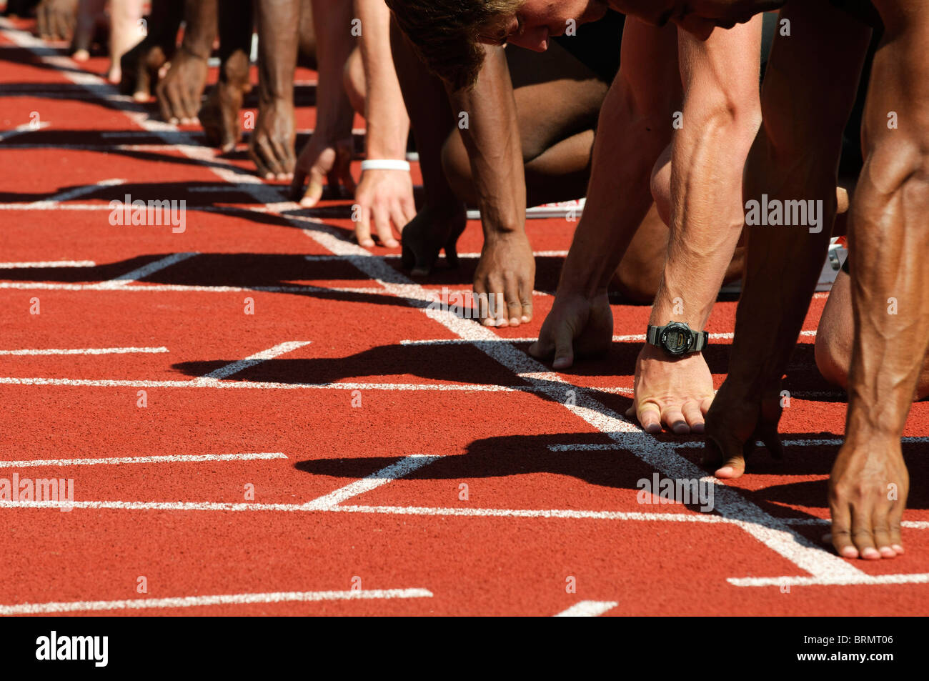 male sprinters line up their hands on the starting line at track and ...