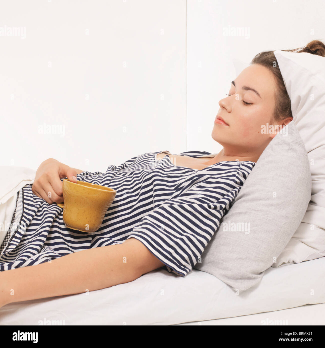 Woman in bed holding a mug Stock Photo - Alamy