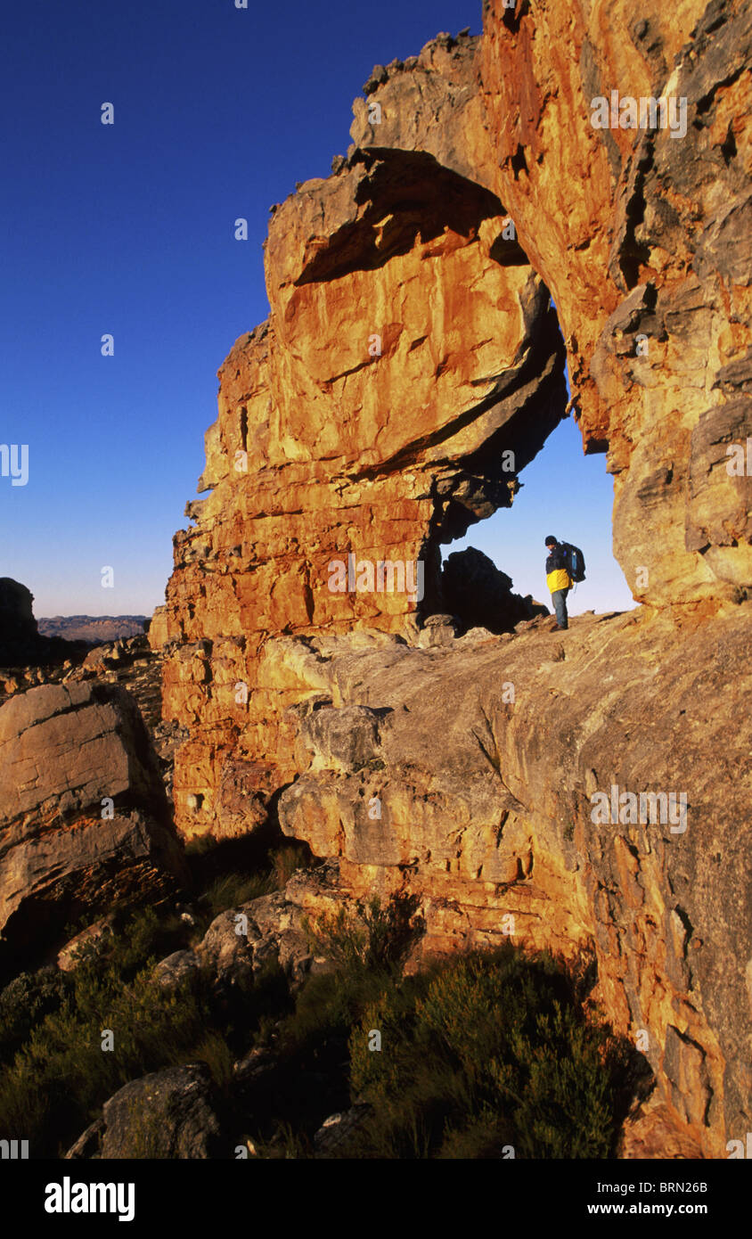 A hiker stands in the Wolfberg arch in the Cedarberg Mountains in the ...