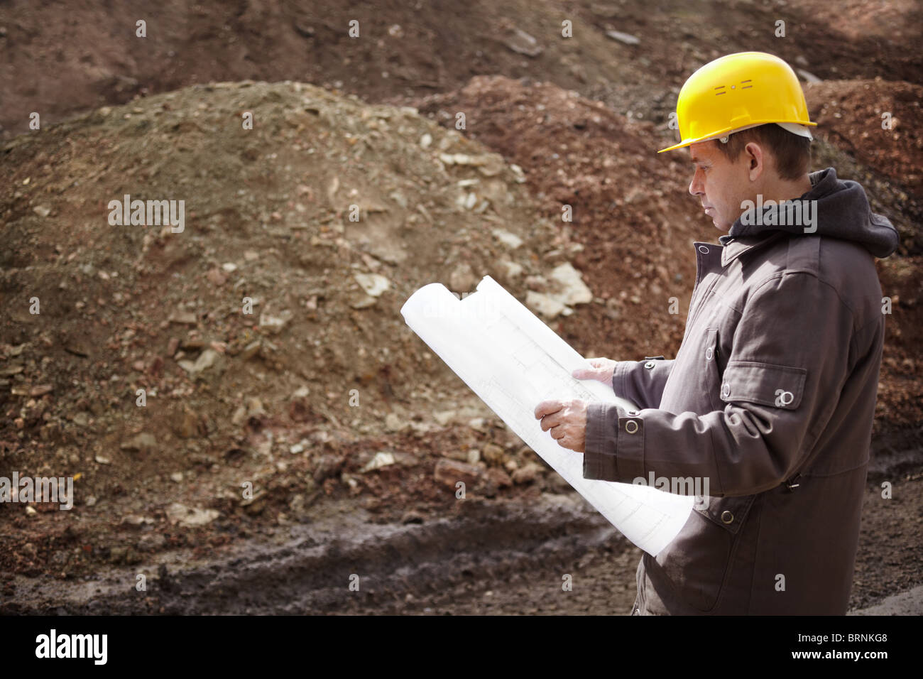 real builder with blueprints on construction site, natural light, focus ...