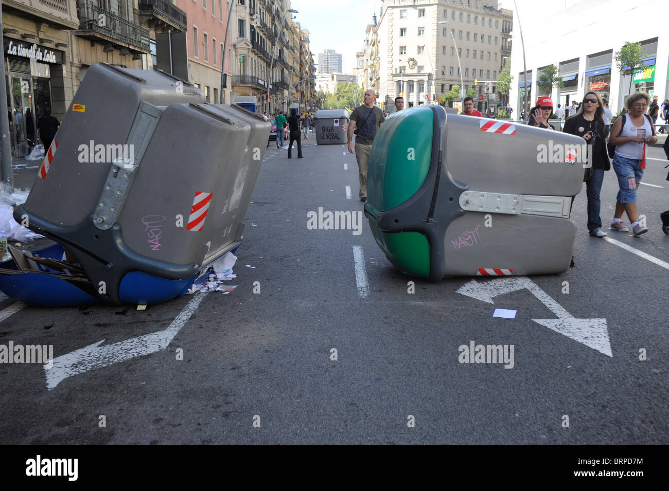 People passing by a barrier of containers during clashes in the city ...