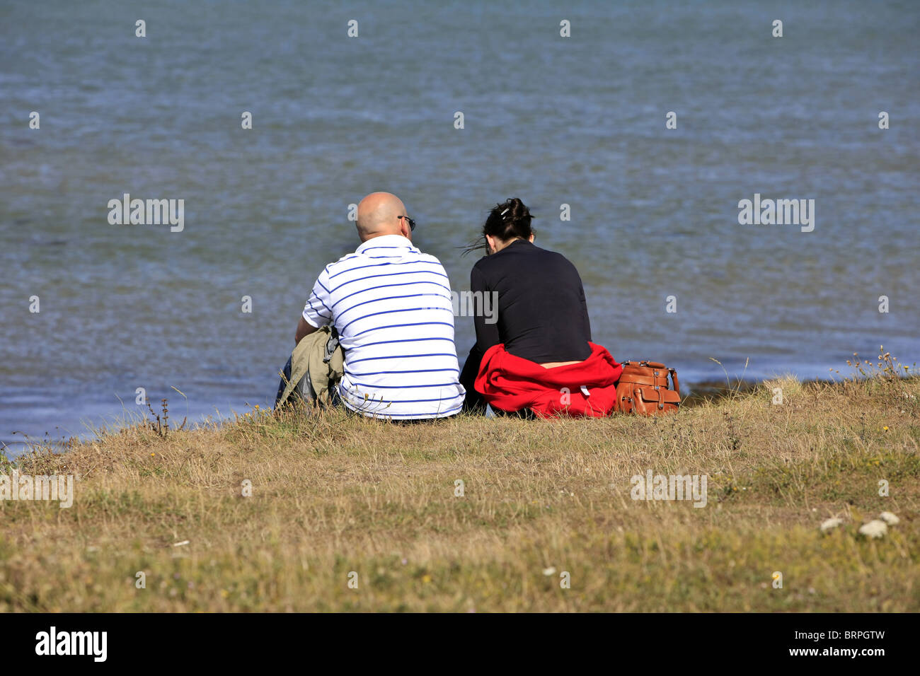 Two people sit quietly at a cliff edge not realising how much danger ...