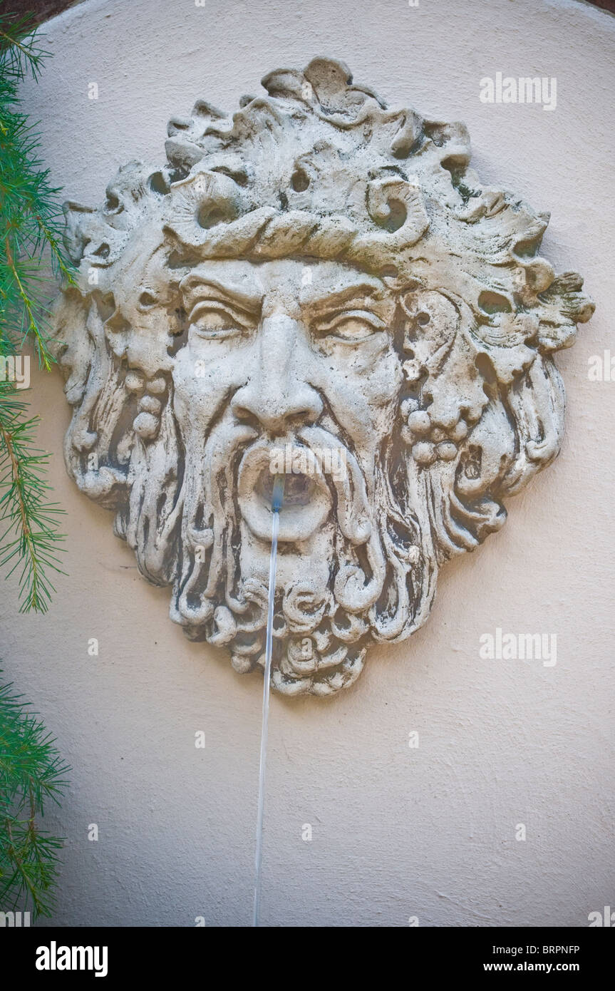 Monumental fountain face spouts water from mouth of god like figure ...