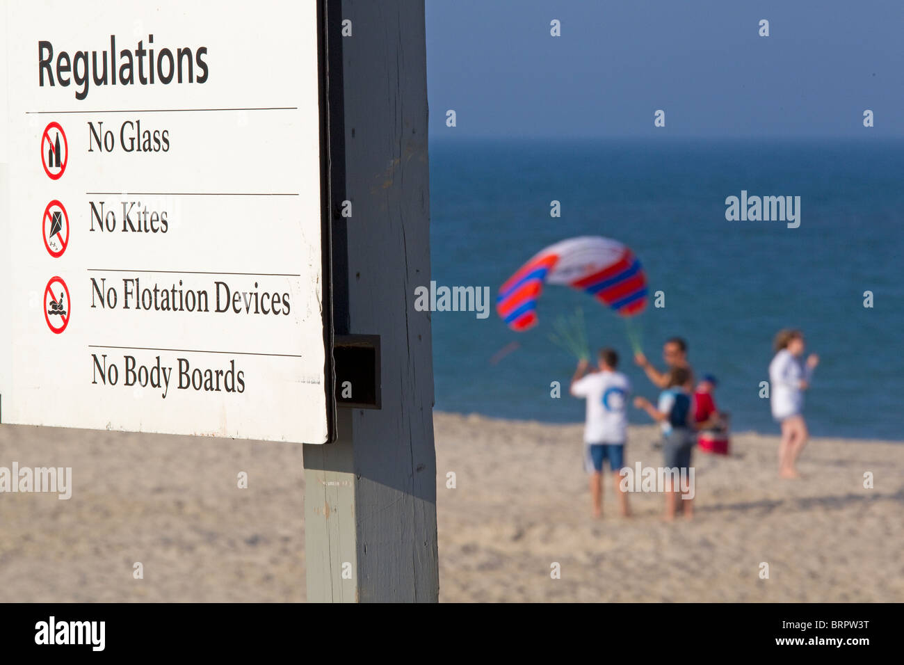 Family flies a kite on the beach despite sign stating no kite flying ...