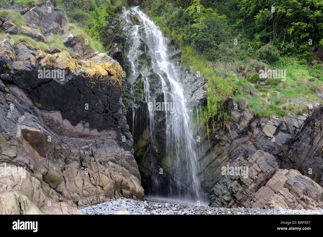 Clovelly Waterfall on a pebble beach at the conservation Village of ...