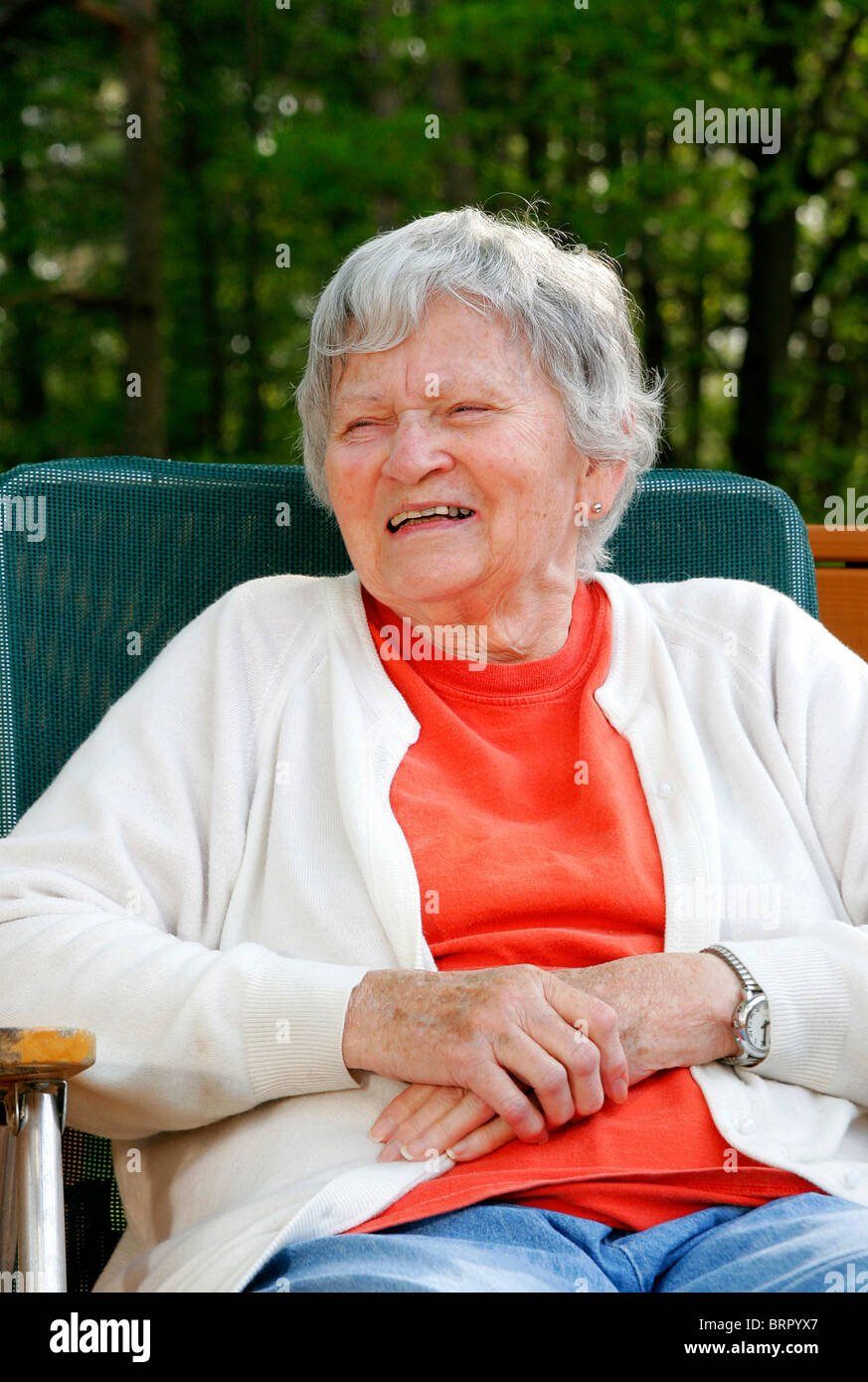 an older lady relaxing outside on the porch laughing and enjoying ...