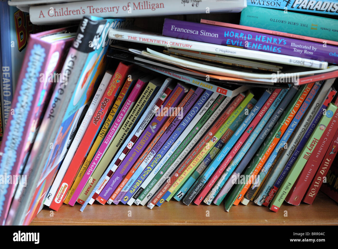 A child's book case with books stacked up and shoved on the wooden ...