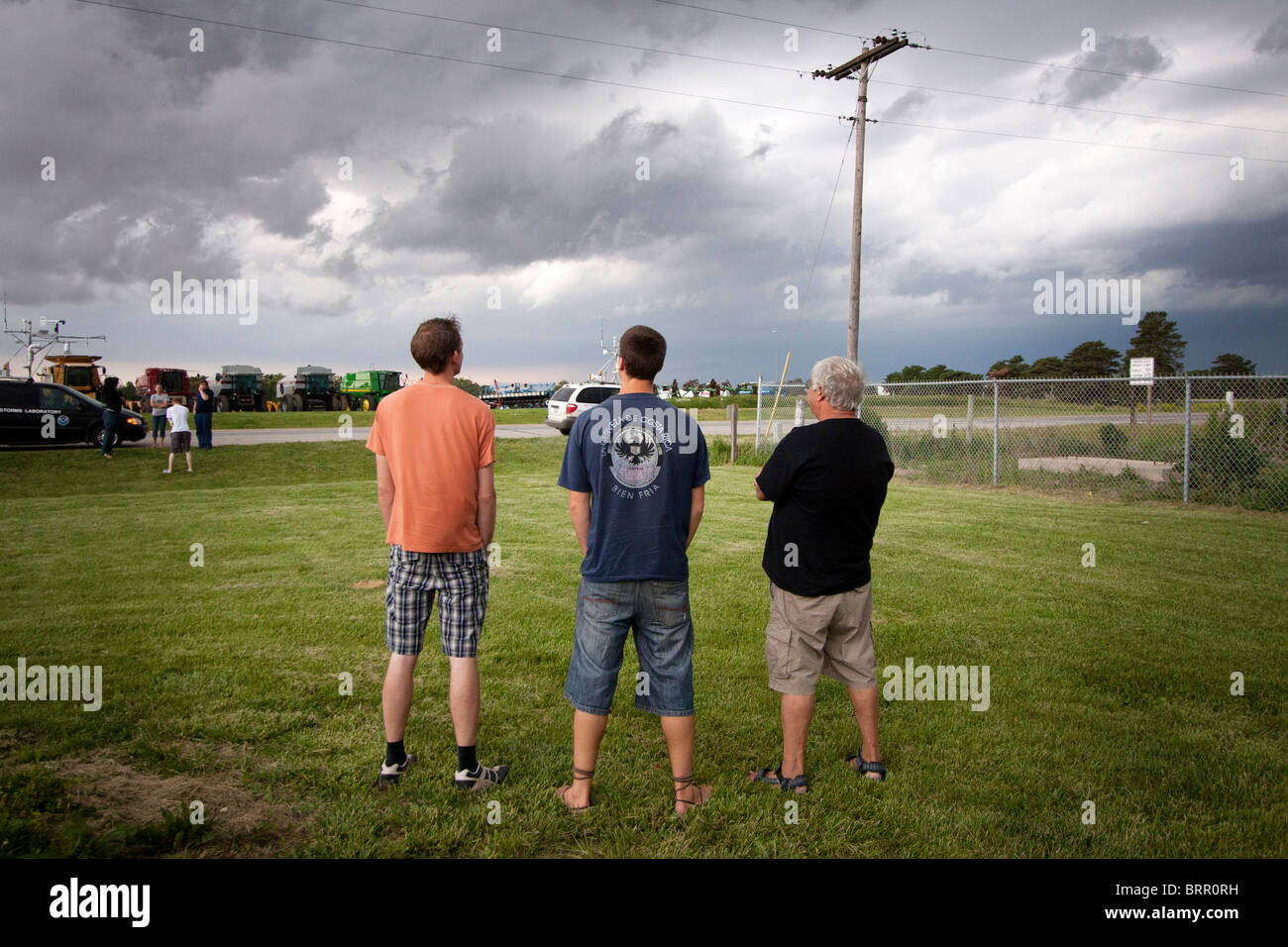 Three storm chasers watch distant dark clouds after a failed storm ...