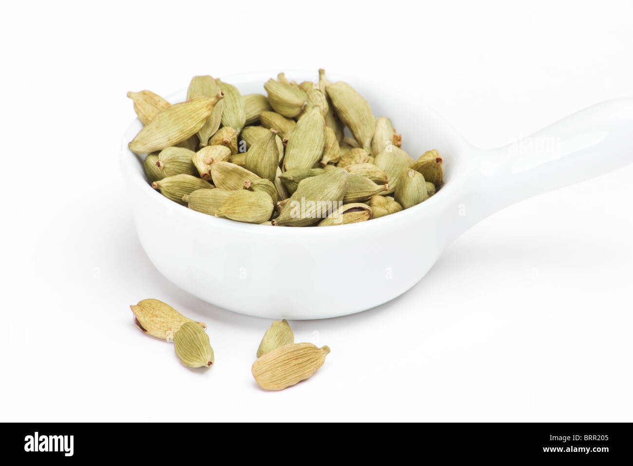 cardamom (Elettaria cardamomum) seeds in a white spoon on white ...