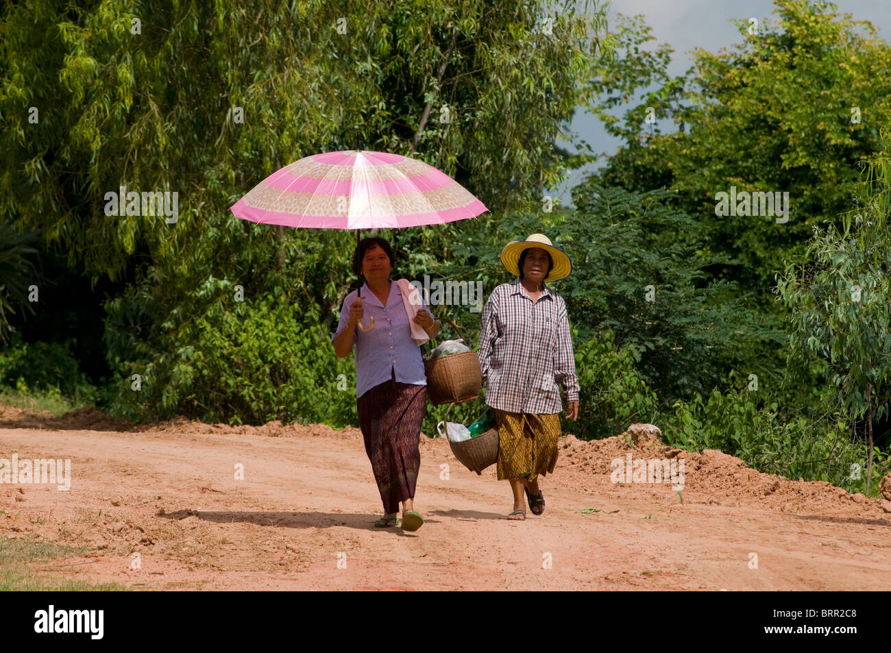 Female villagers walking down a dirt road in Isaan, Northeastern ...