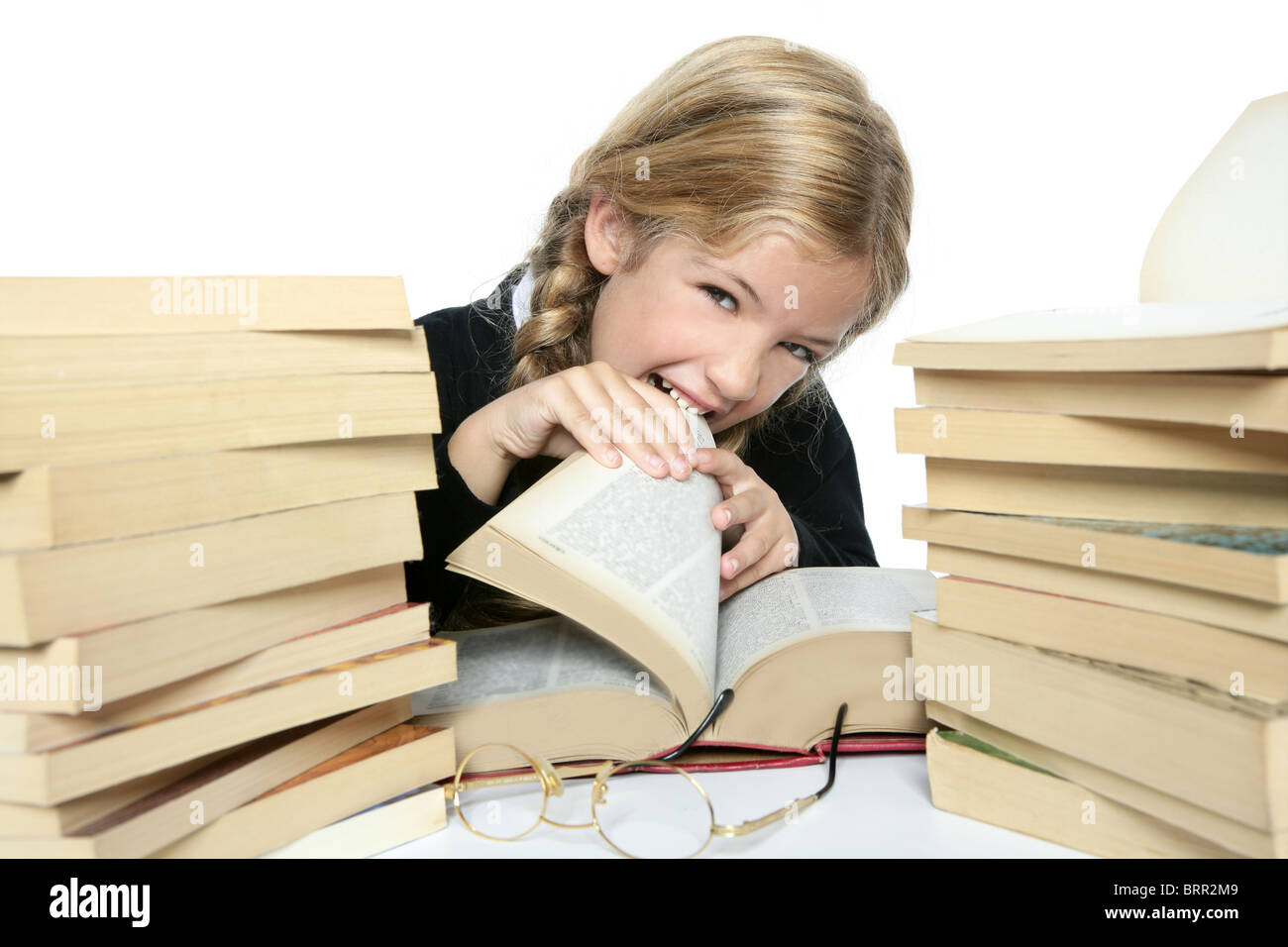 little blond student girl eating her books with a funny gesture Stock ...