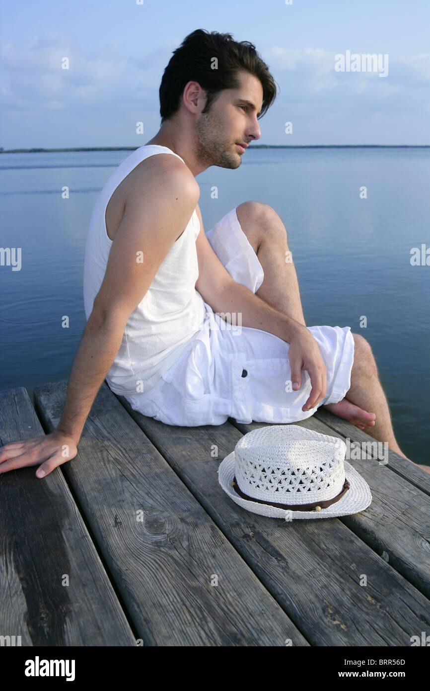 Mediterranean young latin man relaxed on wood pier white hat Stock ...