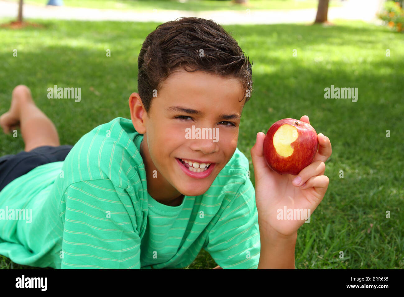 boy teenager eating red apple laying on garden grass outdoors Stock ...