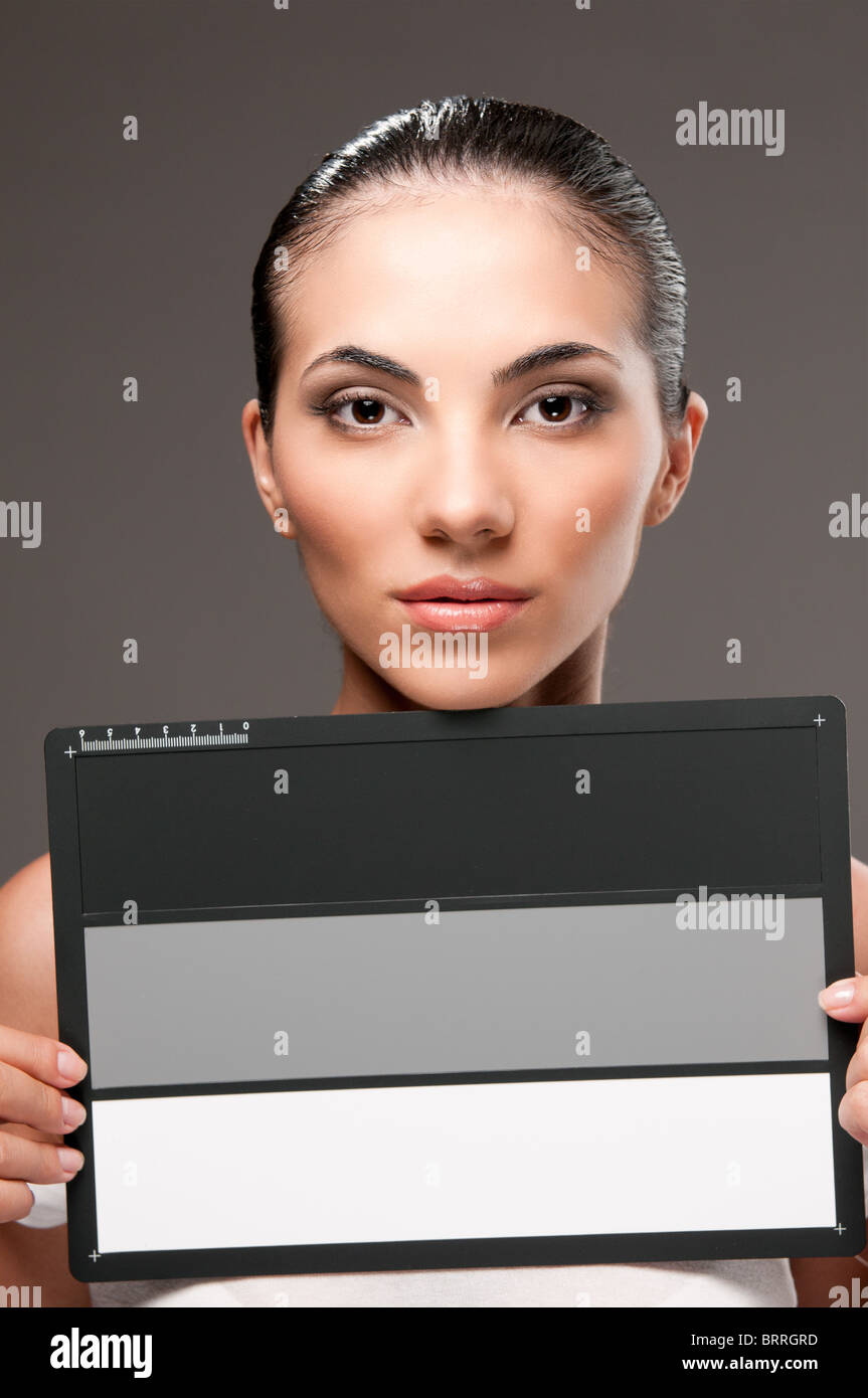 Beautiful young female model holding a color checker for white balance ...