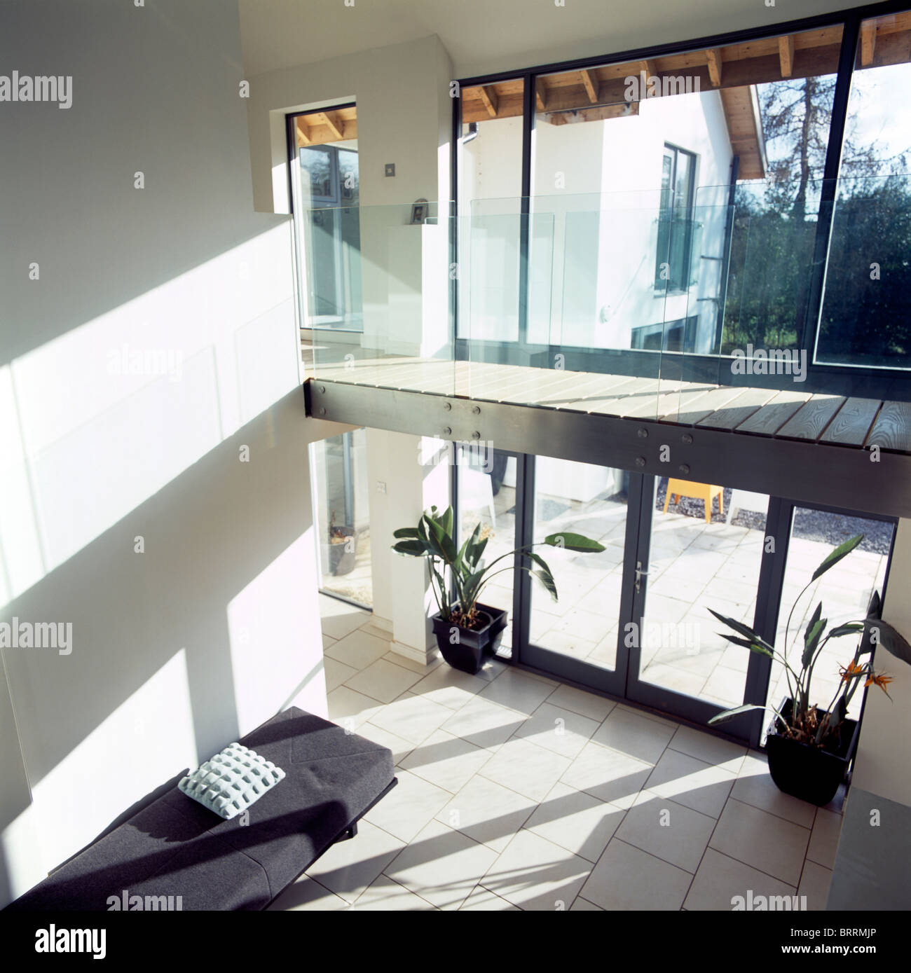 Walkway with glass wall in modern double-height hall with white tiled ...