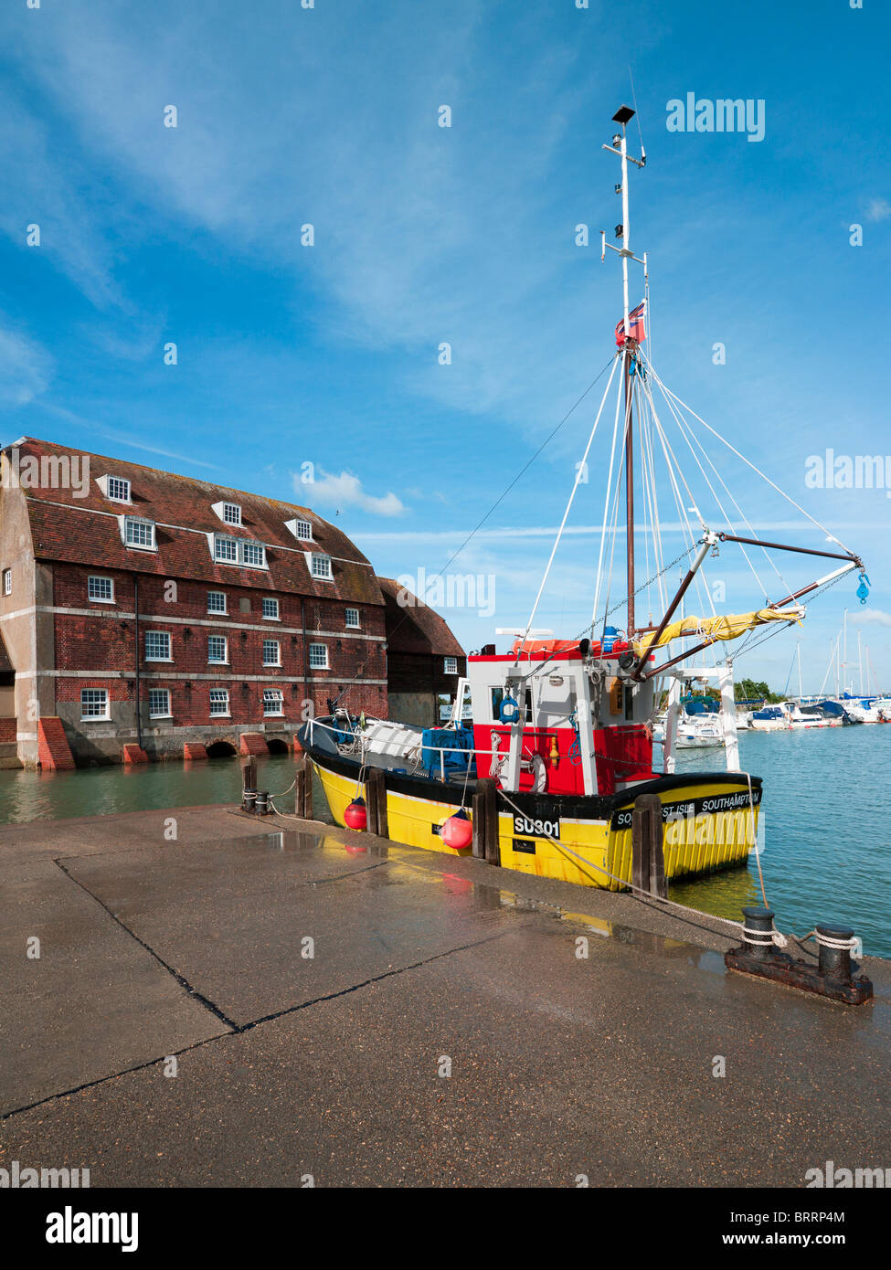 Yellow commercial shell fishing trawler moored alongside quay at ...
