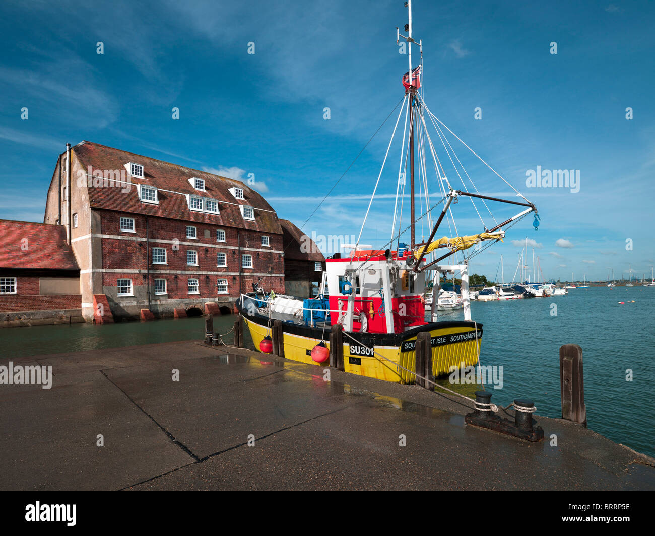 Yellow commercial shell fishing trawler moored alongside quay at ...