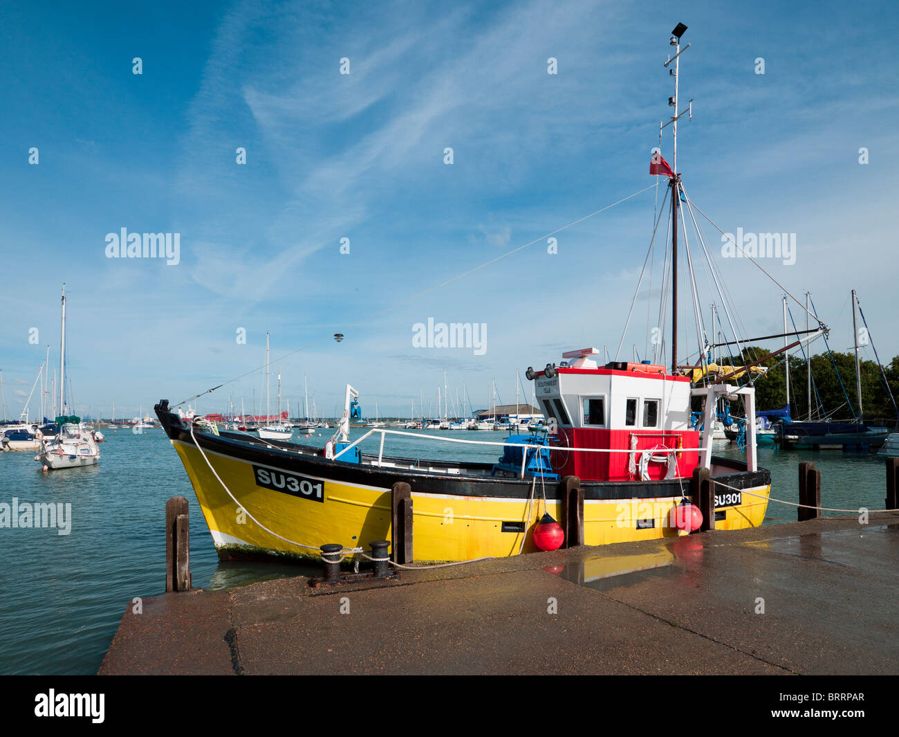 Yellow commercial shell fishing trawler moored alongside quay at ...