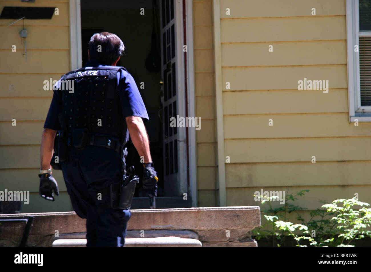Police officer from the Detroit Police Narcotic unit appraoches a house ...