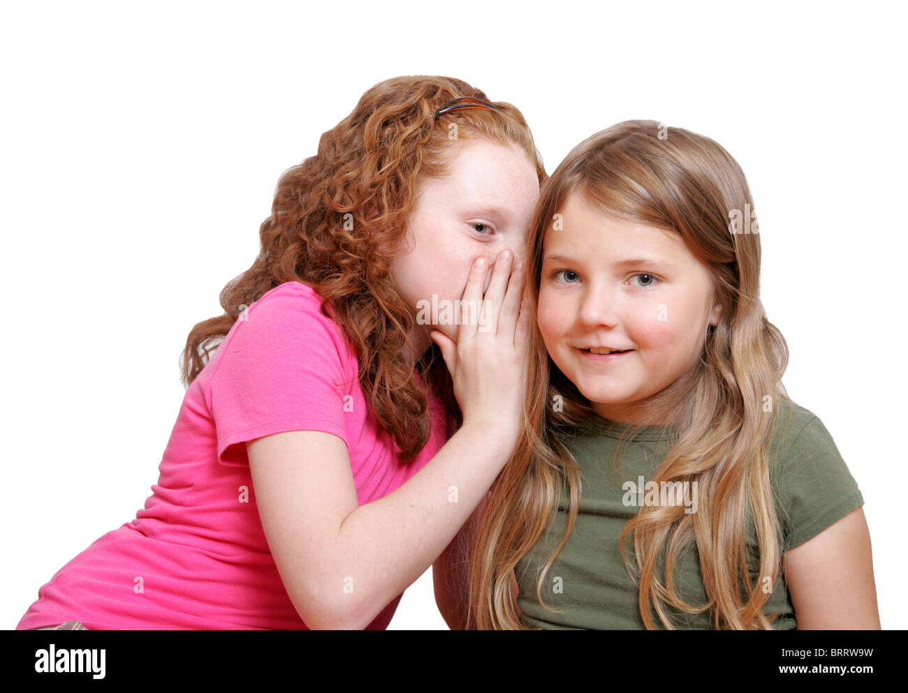 two young girls sharing a secret together over white Stock Photo - Alamy