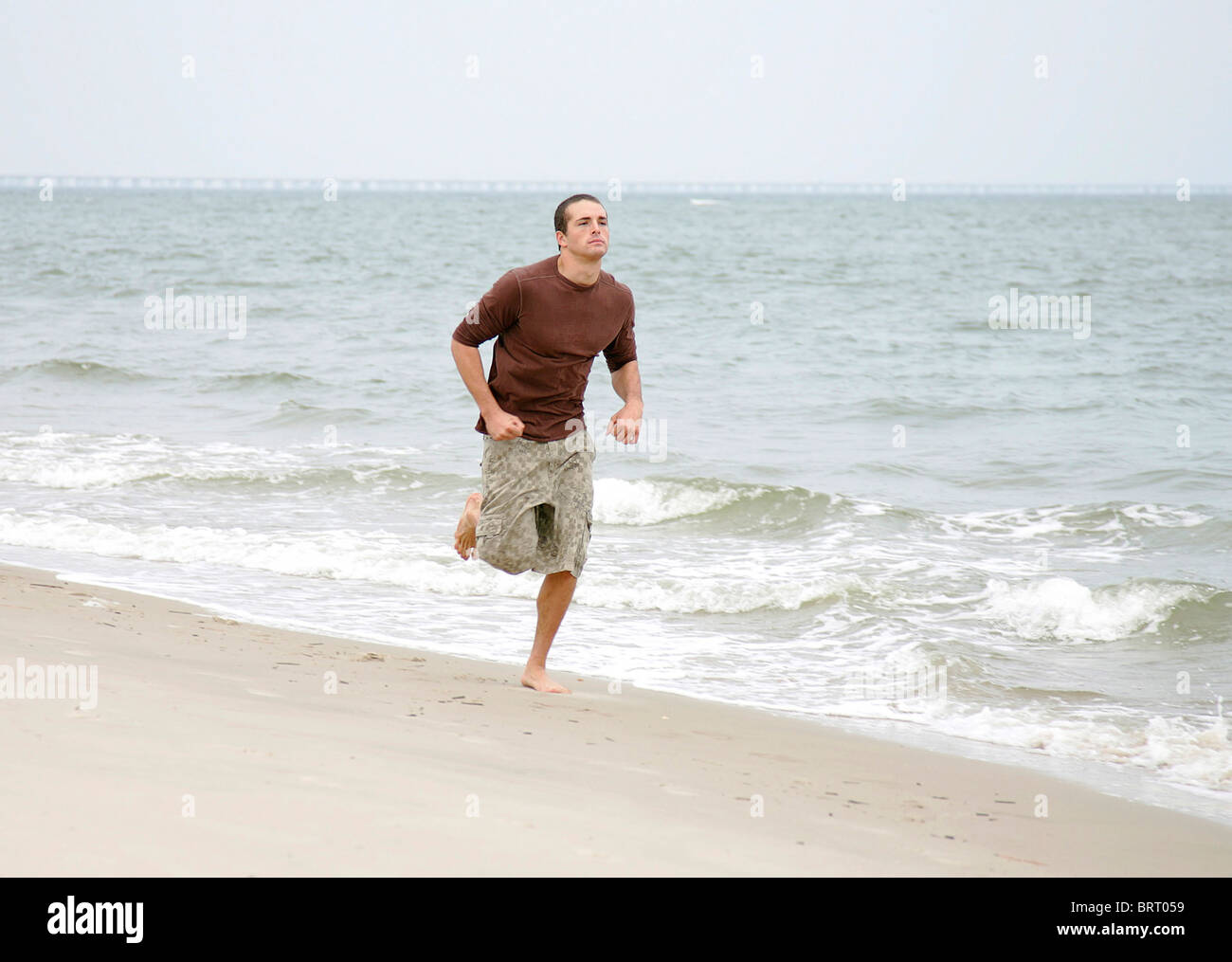 one young fit man running along the beach Stock Photo - Alamy