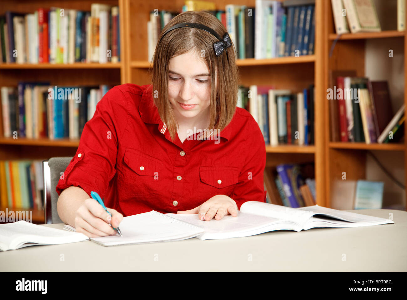 Pretty teen girl doing research in the school library Stock Photo - Alamy