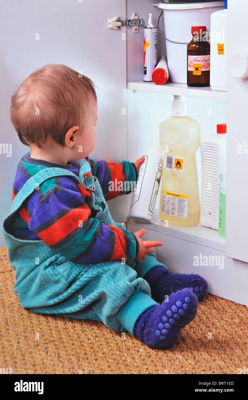 Toddler pulling cleaning agents out of an unlocked cupboard Stock Photo ...