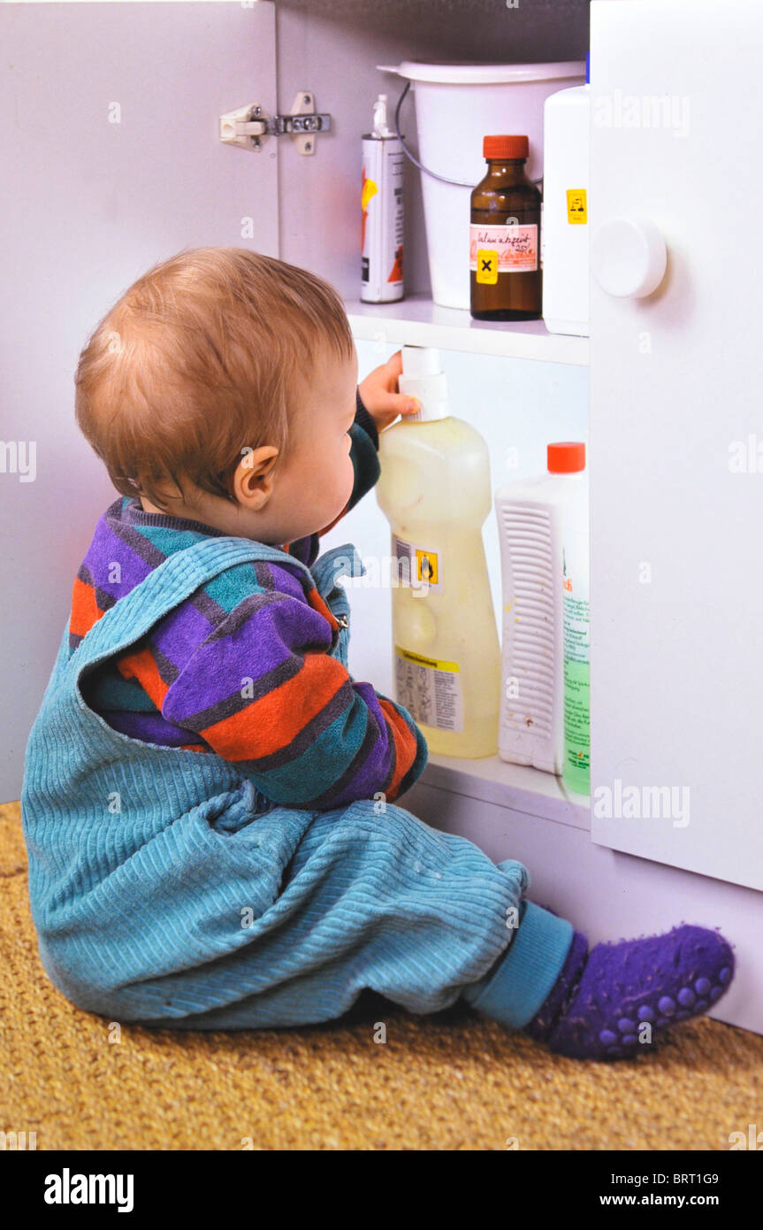Toddler pulling cleaning agents out of an unlocked cupboard Stock Photo ...