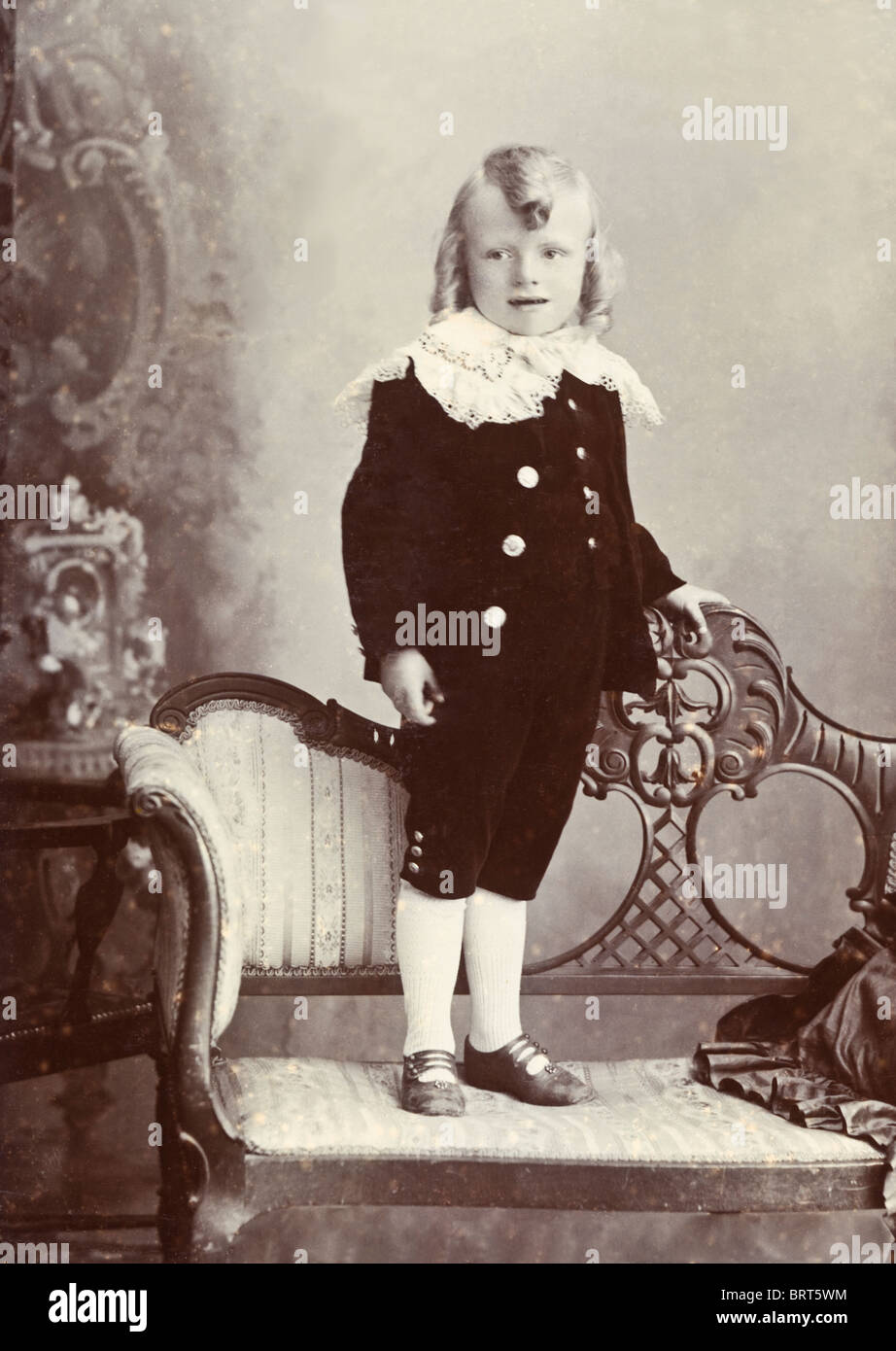 Studio portrait of Edwardian boy with hair in ringlets wearing velvet ...