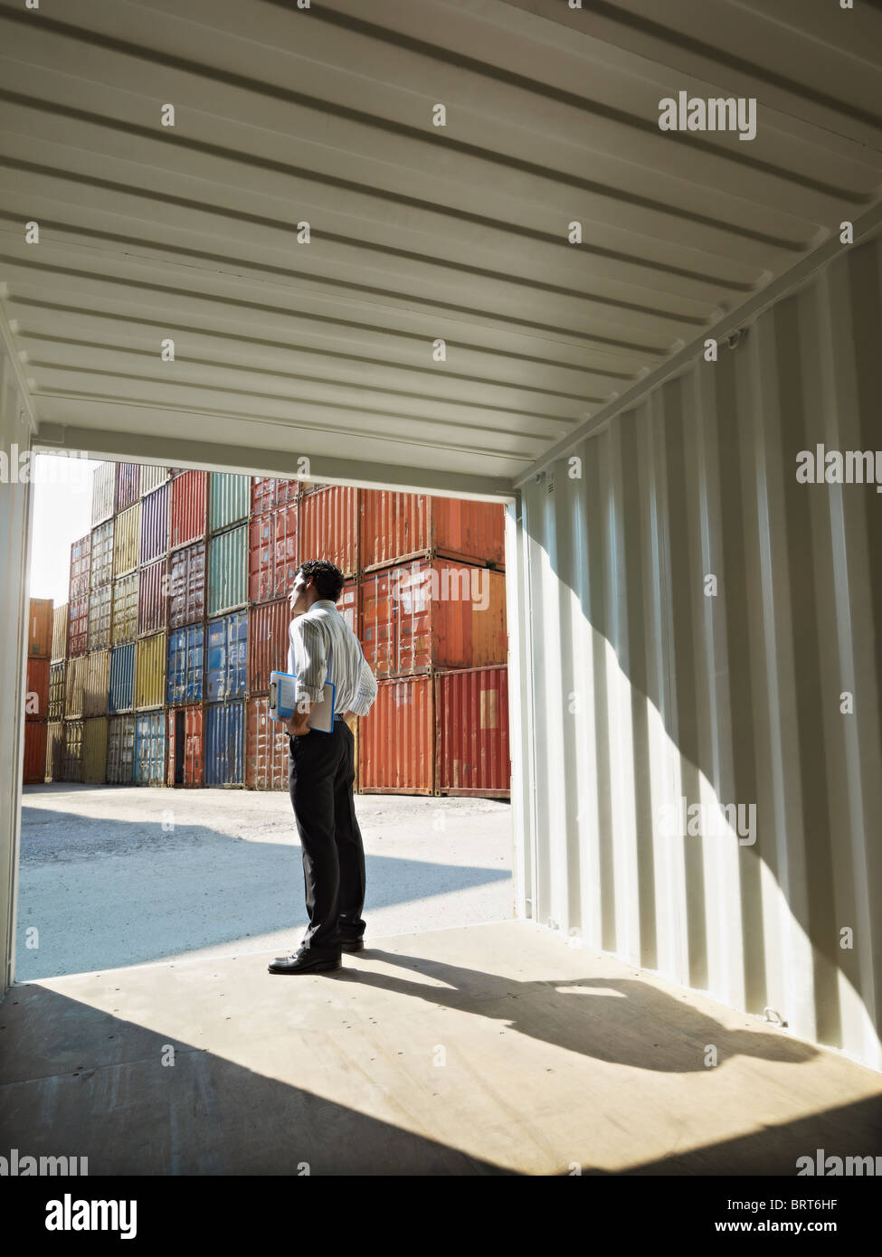 portrait of mid adult businessman standing near cargo container ...