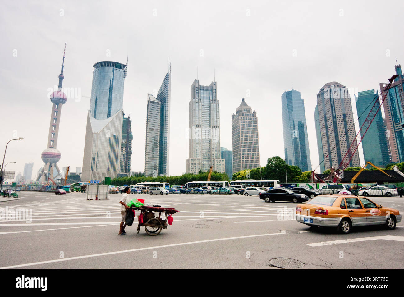 Poor man pushing cart past the modern skyline of Shanghai China Stock ...