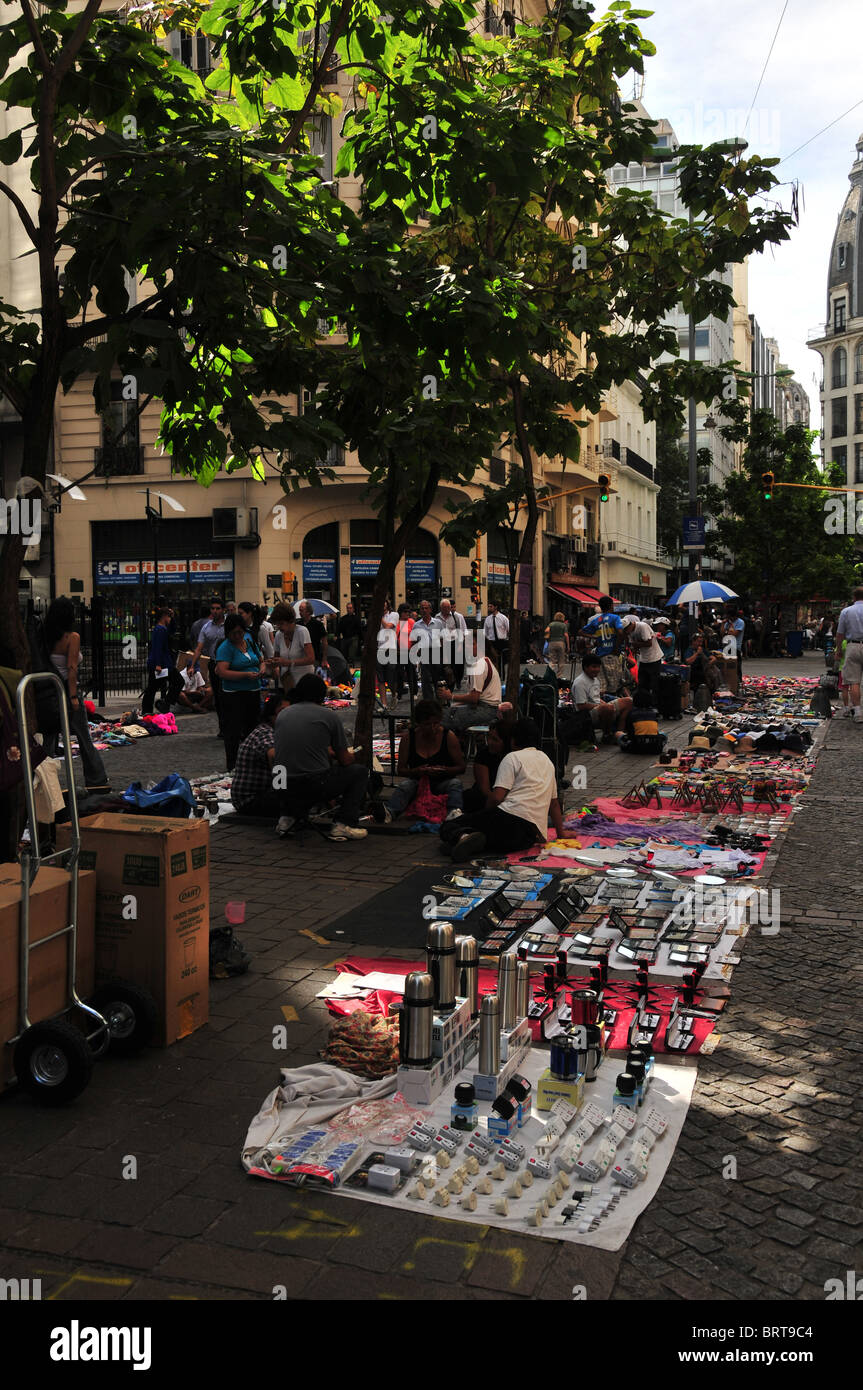 Busy street scene, with market vendors selling crafts, hats, household ...