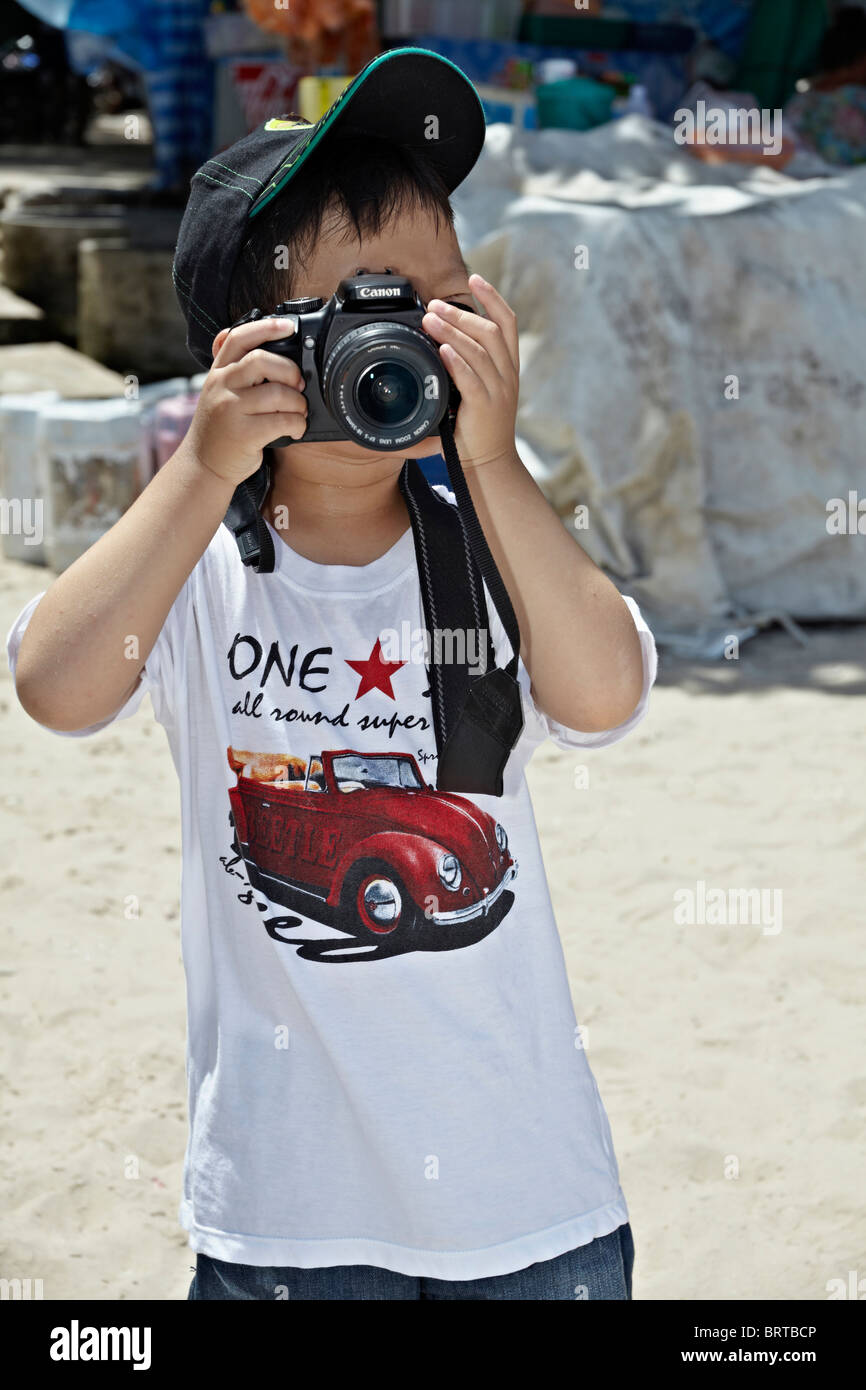 Child using camera. Asian youngster using a Canon digital camera to ...