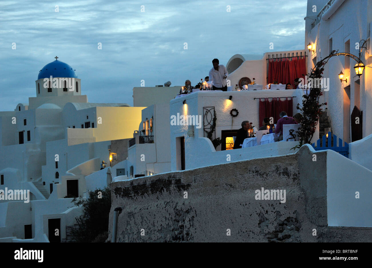 Diners at sunset in a restaurant in the town of Oia on the Greek island ...