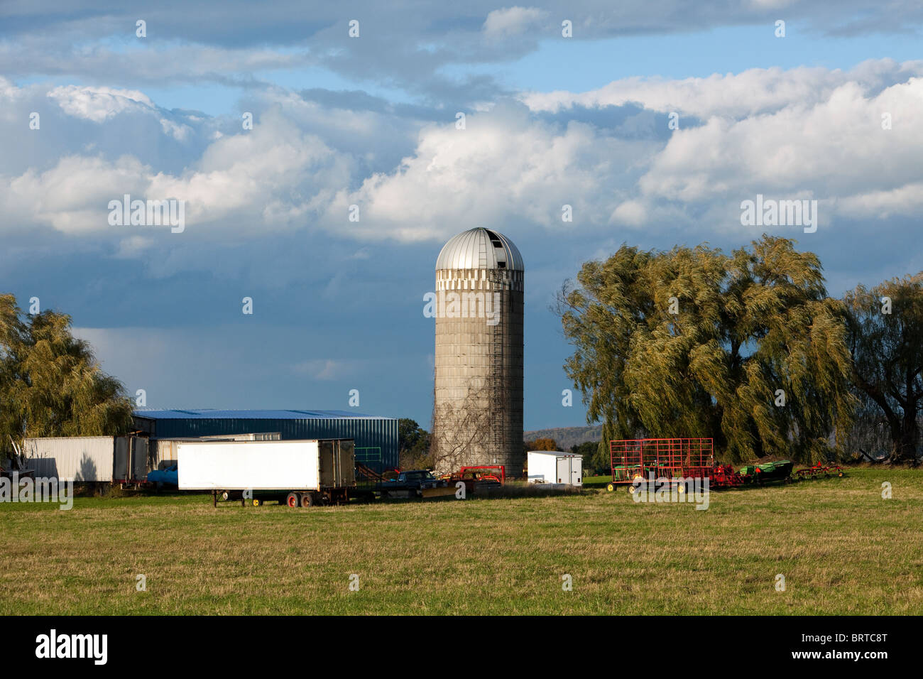 A farm with silos barns and a meadow with gathering storm cloud. Shot ...