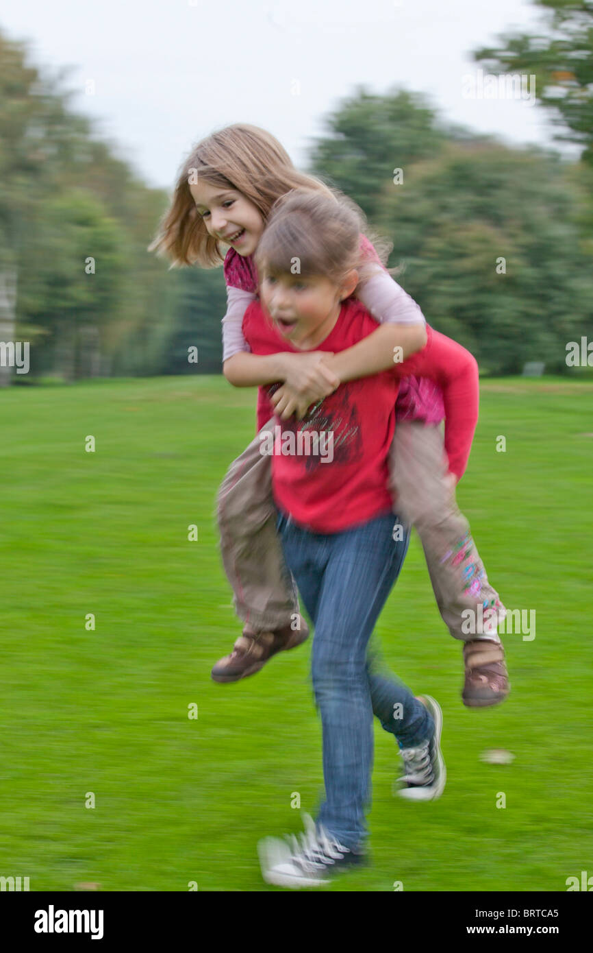 young girl running with her friend piggyback Stock Photo - Alamy